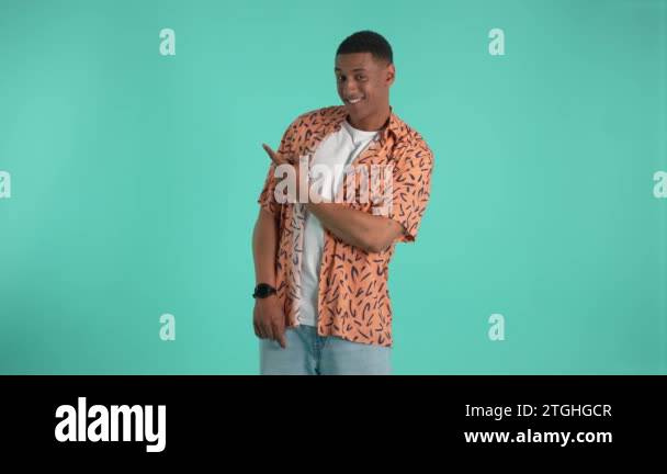 Positive dark-skinned man pointing fingers to different sides like ...