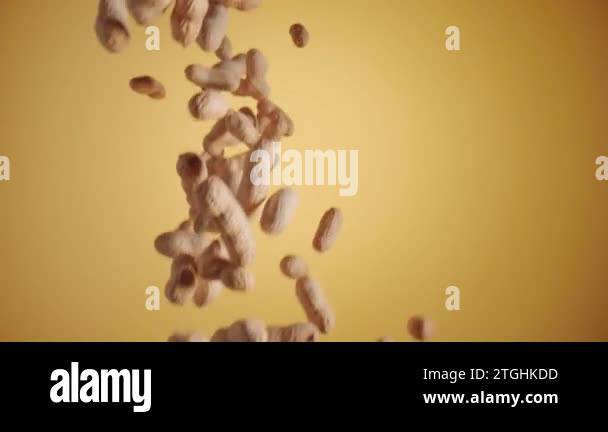 Explosion of dried unpeeled peanuts on yellow studio background. Nut ...