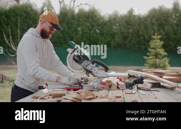 Close up shot of man cutting wood using table saw on construction site ...