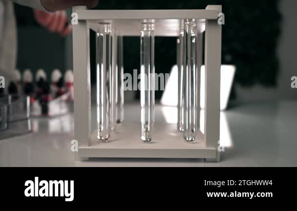 A scientist drips a chemical black reagent into a clear flask of liquid ...