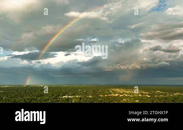 Colorful rainbow against dark stormy clouds forming on gloomy sky ...