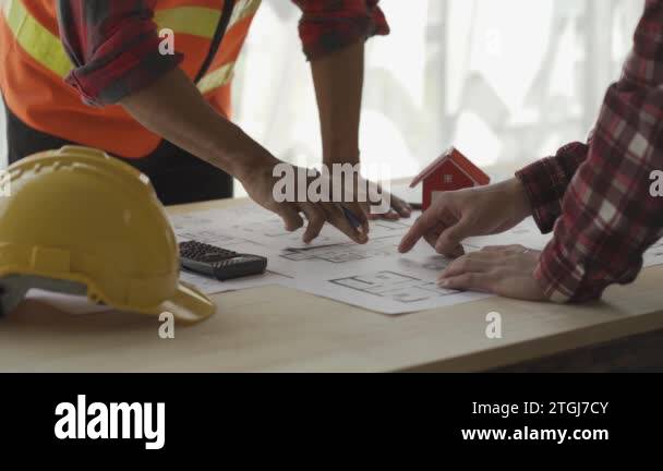 Architect and foreman looking at blueprints and planning building ...