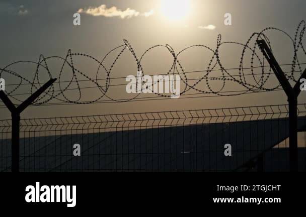 Barbed wire fence around the solar power plant during sunset. Mesh ...