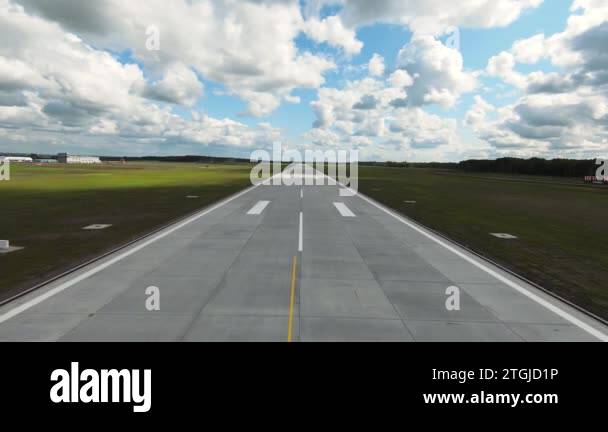 Empty asphalt runway with white markings and light equipment by sides ...