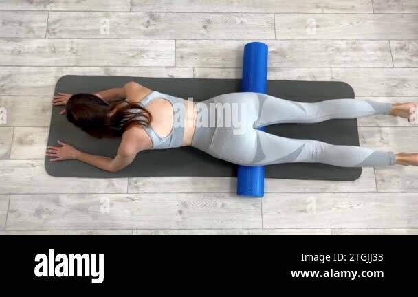 MFR. A young female athlete rolls her quadriceps on a foam roller ...