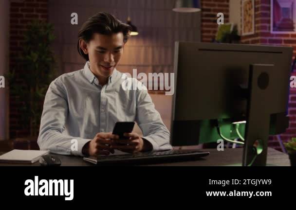 Asian man browsing internet on smartphone and texting messages on work ...