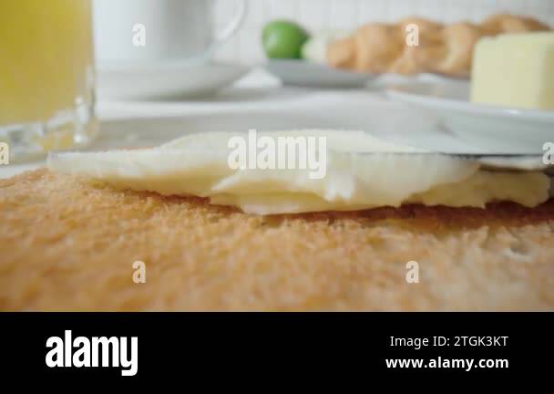 Knife spreading white butter on a toasted piece of crispy toast. Soft ...