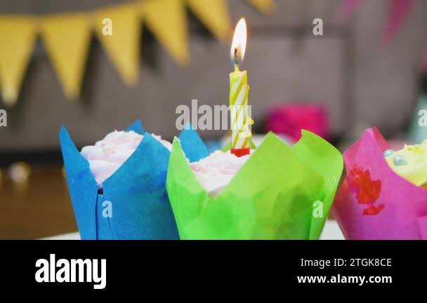 Close-up of multi-colored festive muffins with a burning candle and ...