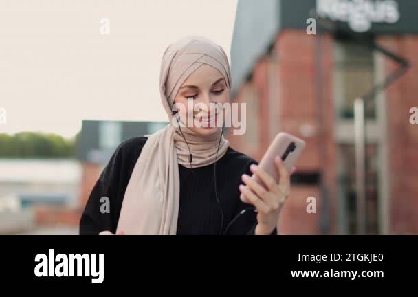 Music streaming platform concept. Joyful muslim girl in hijab wearing ...