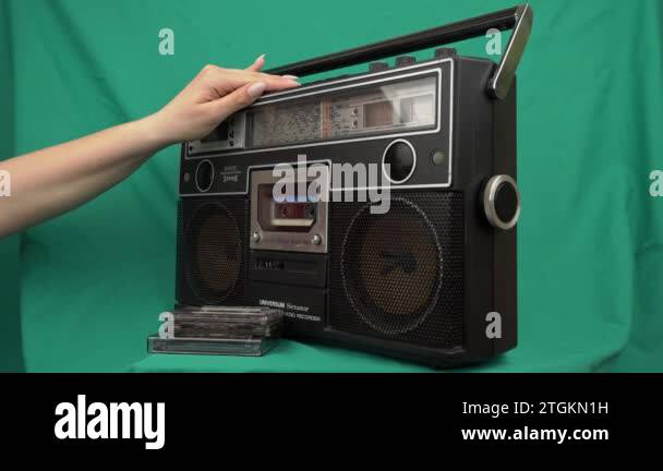 Girl takes out a vintage cassette into a black radio tape recorder on a ...