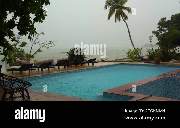 Tropical summer rain falling big rain drops falling down on swimming ...