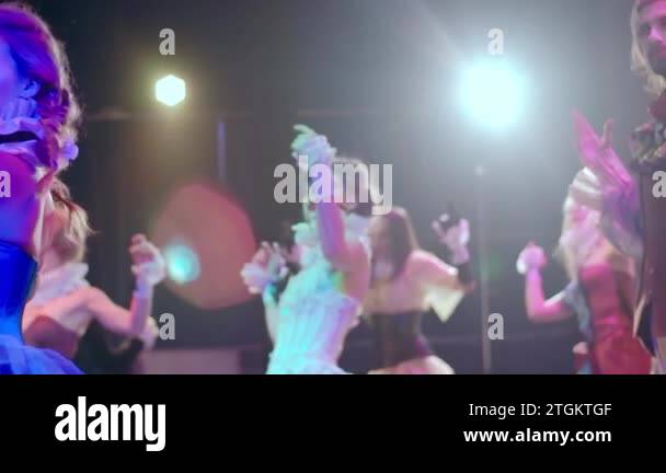 Young actress in dress passing dancing with troupe on stage at backlit ...
