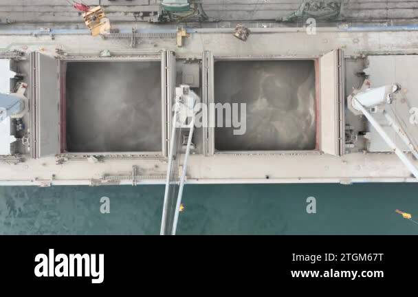 Loading dry cargo ship of sunflowers by cranes in port. Aerial view loading into holds of sea ...