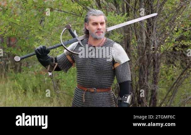 Medieval warrior in armor with gray hair and a scar on his face shows a ...
