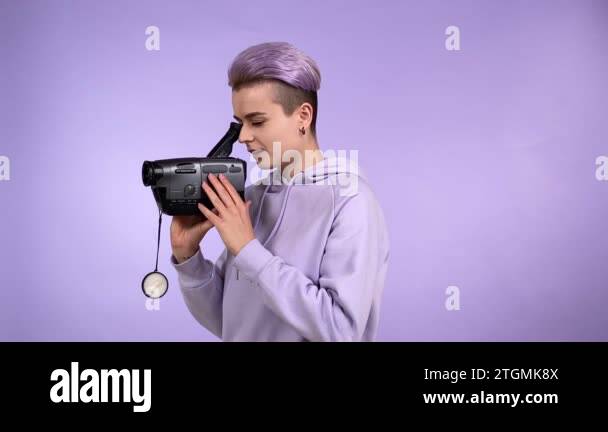 Young adult person with dyed purple hair holding, using old VHS video ...