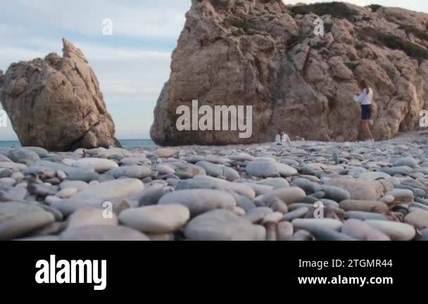 A woman takes a photo of another woman at the beach at the Petra tou ...