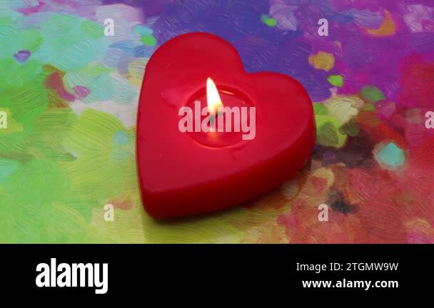 Red heart shaped candle and candlelight isolated on a painter's color ...