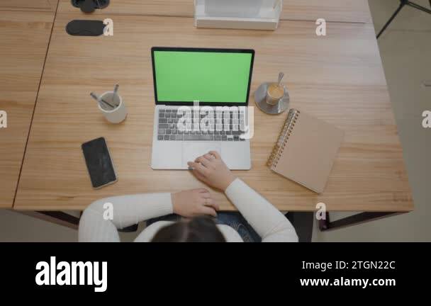 Office table with green screen laptop computer and female hands taping ...