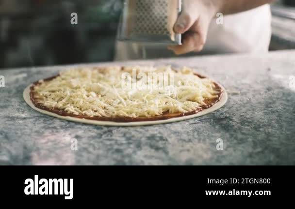 Close up for cooks hands grating cheese on the pizza Four Cheeses.Chef ...