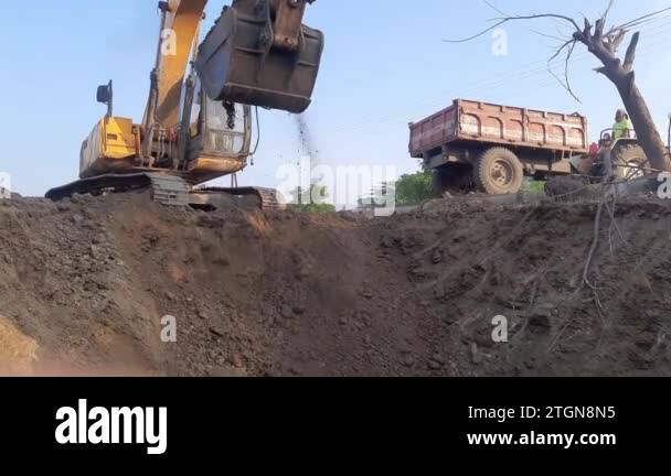 A poclain machine excavator machine loads Moorum soil into a tractor at ...