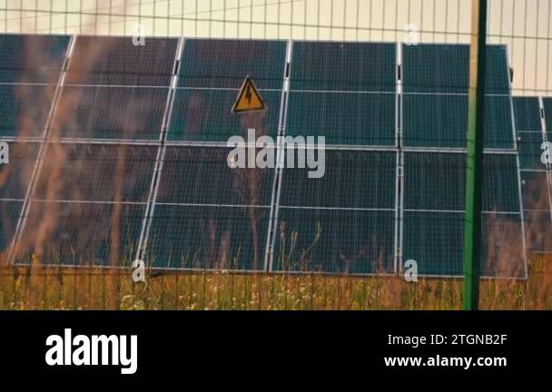 Solar panels are located in a field behind a barbed wire fence. Solar ...