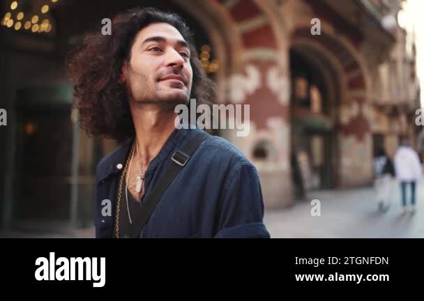 Young attractive italian guy with long curly hair and stubble looks ...