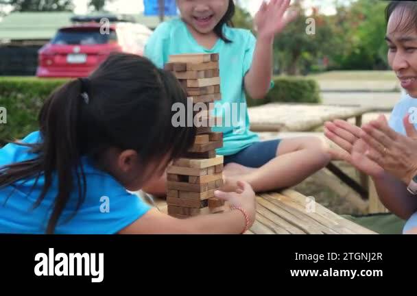 Excited kids and mom playing Jenga tower wooden block game together in ...
