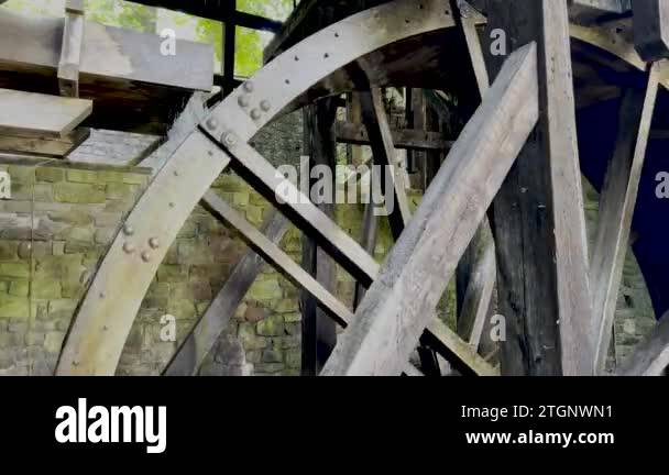 4K footage of a rustic turning colonial water wheel in a stone ...