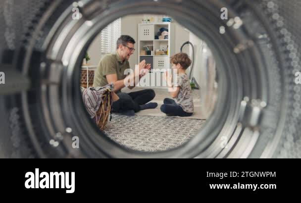 A view through the washing machine drum into the bathroom. A son and ...