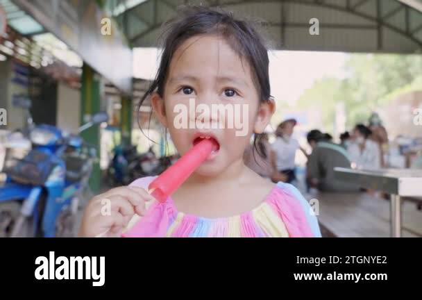 Happy Asian little girl eating popsicle at summertime, young woman ...
