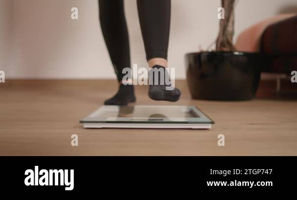Woman in socks stepping on scale to see her weight. Girl wants to know ...