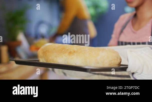 Video of happy diverse couple baking, woman taking bread out of oven in ...