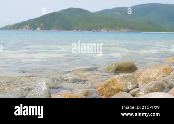 Stones under the waving sea water, tropical island on background 4k uhd ...
