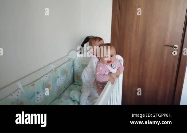 Two fraternal twins sisters having fun in crib. Two babies standing in crib Stock Video Footage ...