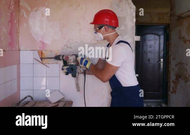 Contractor removes of ceramic tiles facing of a wall. Workman doing ...