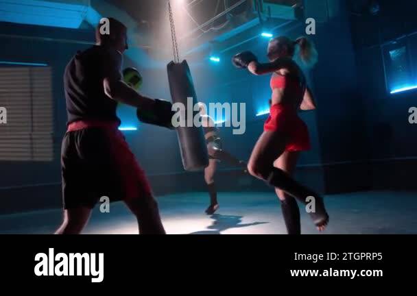 Kickboxing training. In foreground woman fighter trains punches and ...