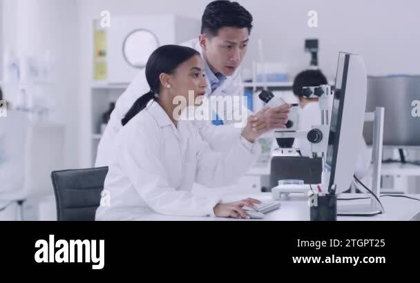 Two scientist using a computer and microscope while conducting medical ...