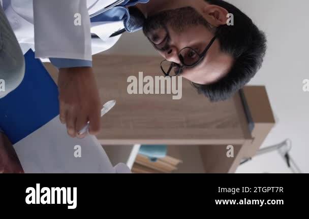 Vertical video. Patient chart. Busy doctor. Working routine. Smart man ...