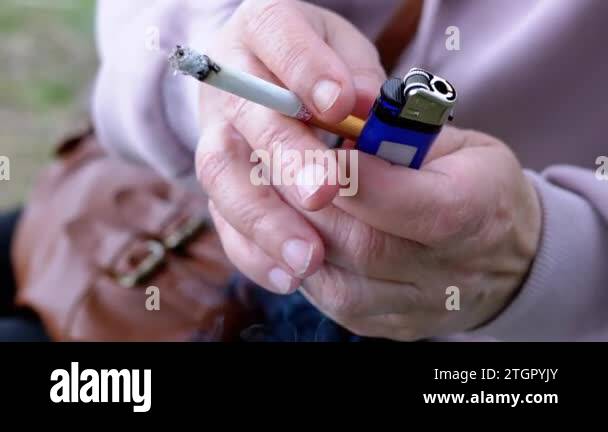 Woman Holding a Cigarette and a Lighter in Hands Sitting in Nature on ...
