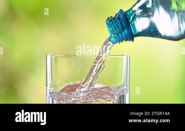 Super Slow Motion Detail Shot of Pouring Pure Water into Glass on Green ...