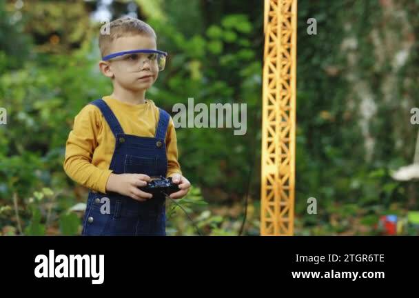 Portrait of little boy with remote control crane beam in an industrial ...