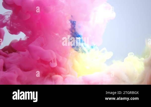 Pink and blue colored ink burst in water and form an abstract smoke ...