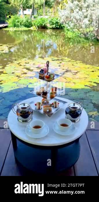 Afternoon tea at a water pond, high tea in a tropical garden with ...