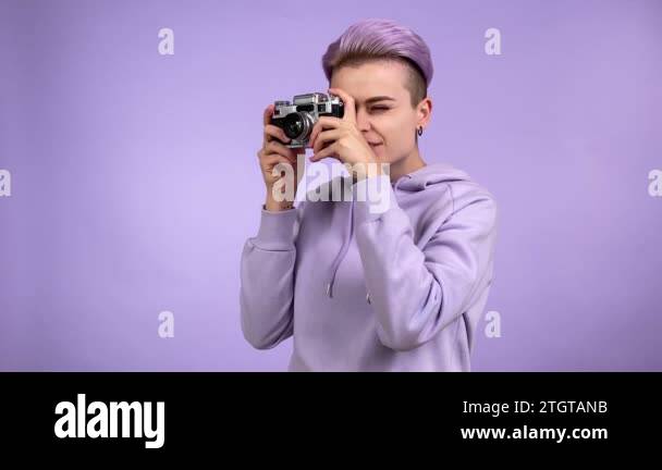Positive young adult woman taking pictures with old-fashioned film ...