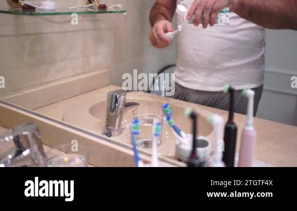White man pouring toothpaste into an electric toothbrush Stock Video ...