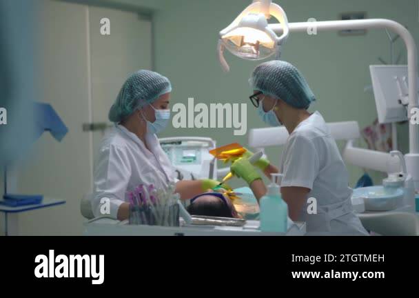 Side view positive dental assistant using curing light for filling ...