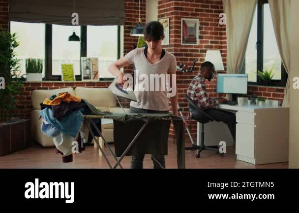 Housewife using iron with steam to smooth out clothes after washing ...