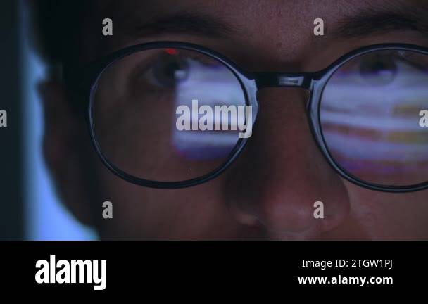 Close up male working at computer late at night, reflection in glasses ...