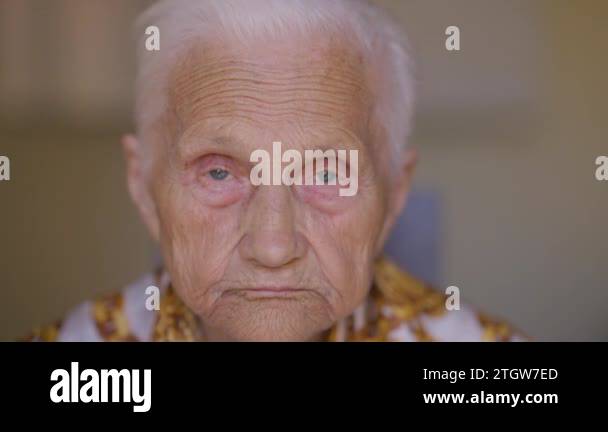 Close-up wrinkled face of old Caucasian grey-haired woman with grey ...