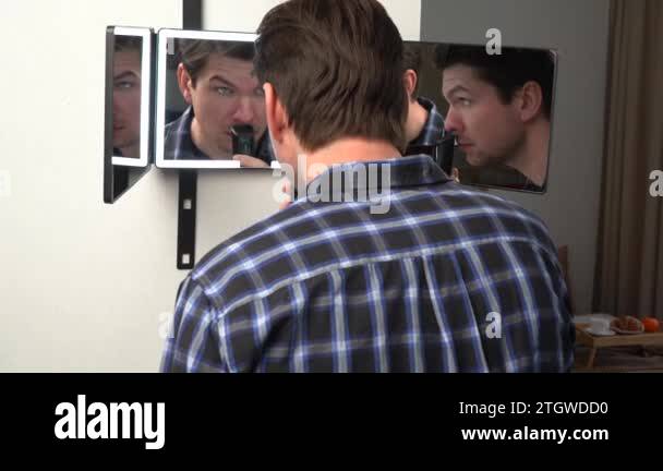 A man hangs a smart mirror on the door. A man shows off his beauty in ...